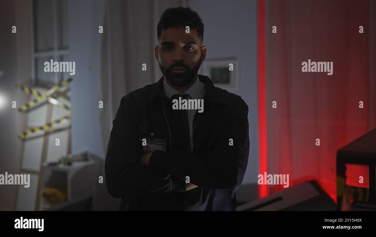 Hispanic detective standing solemnly in a dimly-lit indoor crime scene ...
