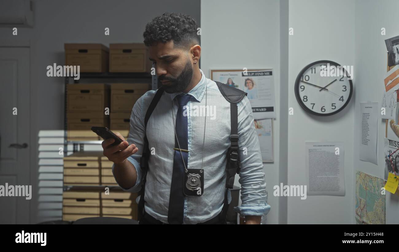 Hispanic detective in a police station office, holding smartphone, with ...