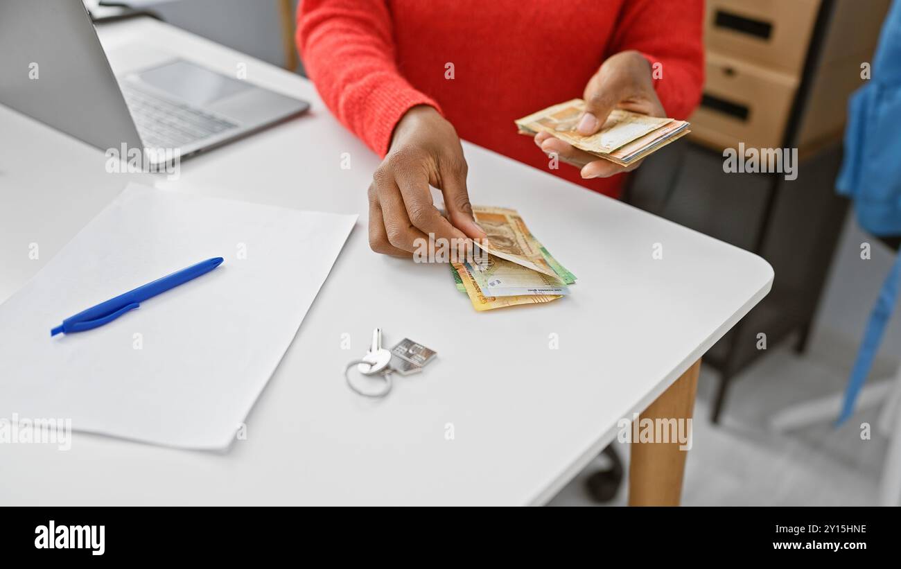 African woman counting south african rands in a modern office setting ...