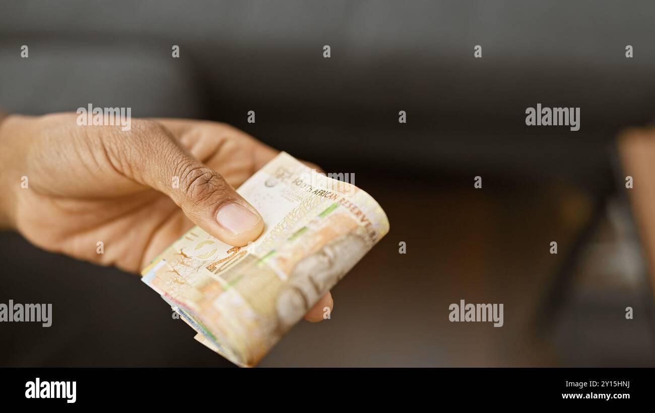 Hand holding south african rand notes indoors, indicating finance ...
