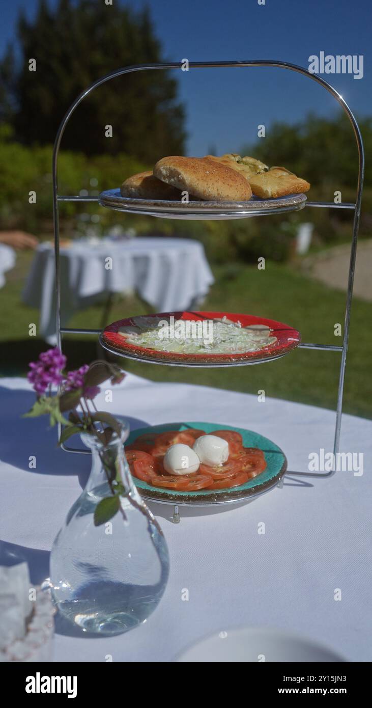 Outdoor dining scene with various appetizers displayed on a tiered tray ...