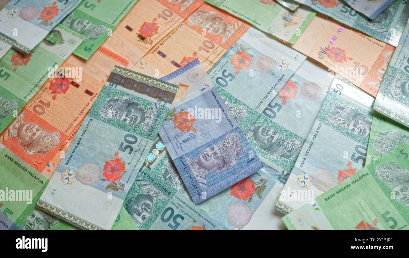 Malaysian banknotes of various denominations are scattered across a ...