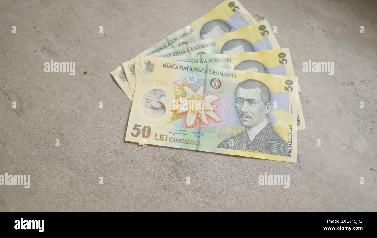 Romanian money banknotes of 50 lei lie neatly on a concrete surface ...