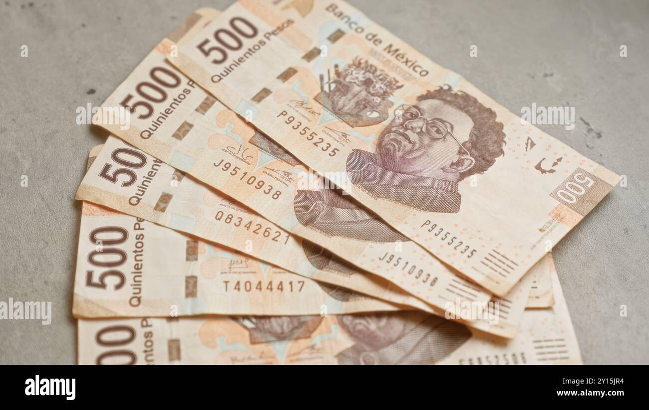 Mexican 500 pesos banknotes are laid out on a concrete surface ...