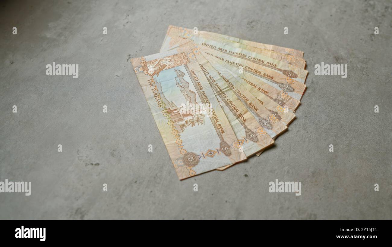 Uae dirhams banknotes spread on a concrete surface, showcasing middle ...