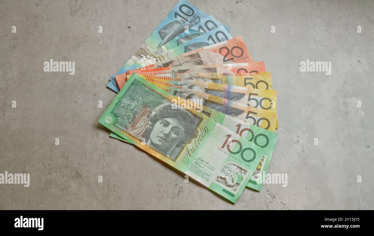 Australian banknotes of various denominations neatly arranged on a gray ...