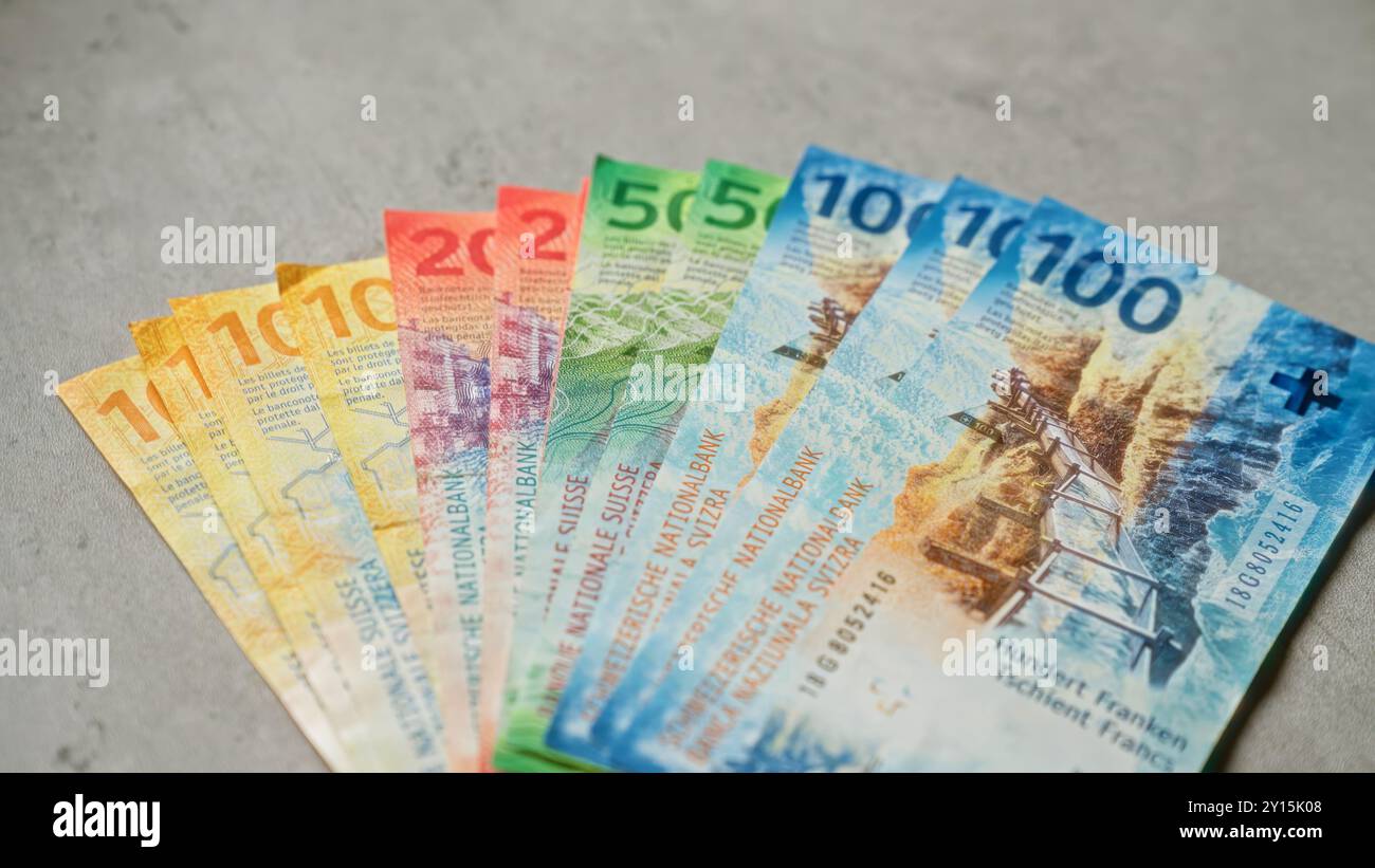Swiss franc banknotes spread out on a concrete surface, showcasing ...