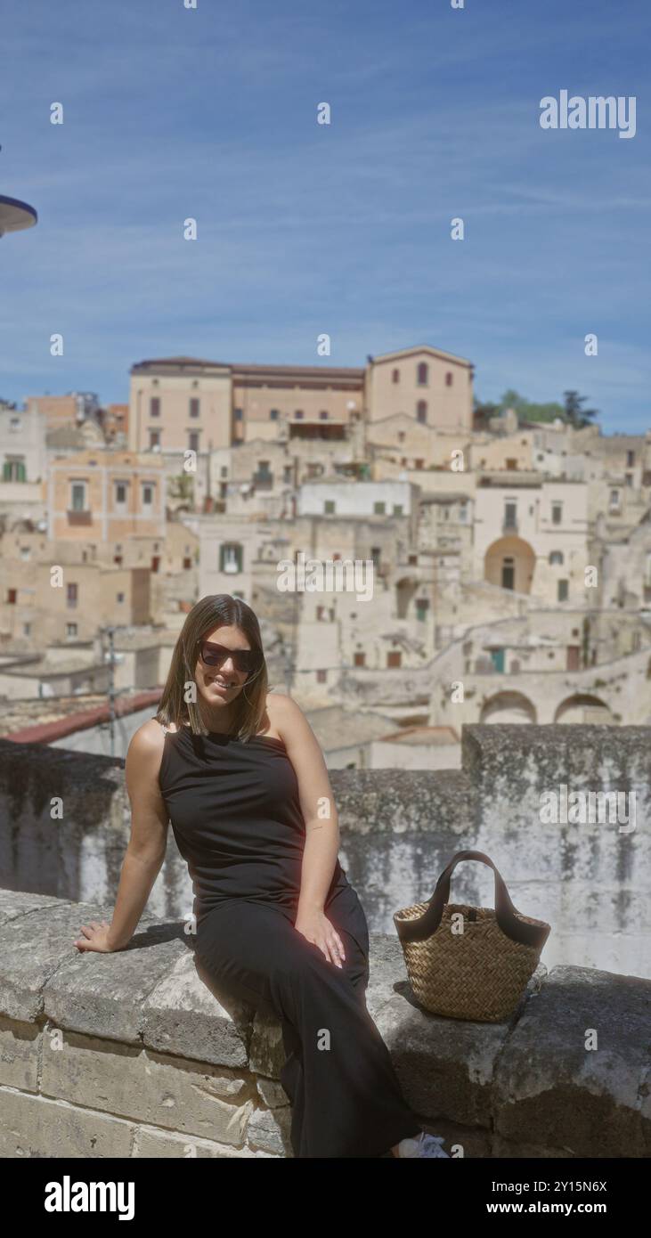 A beautiful young hispanic woman sits at a viewpoint in the old town of ...