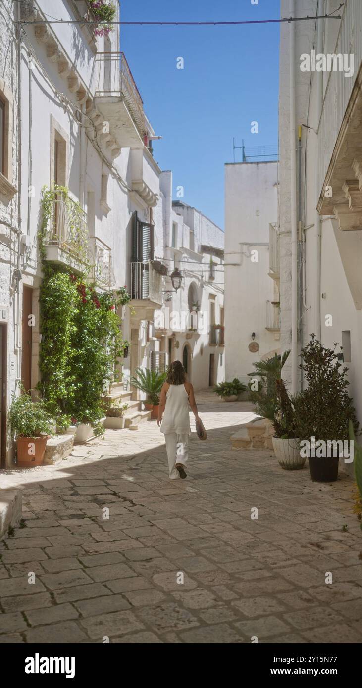 A young hispanic woman walks through the charming, white streets of the ...