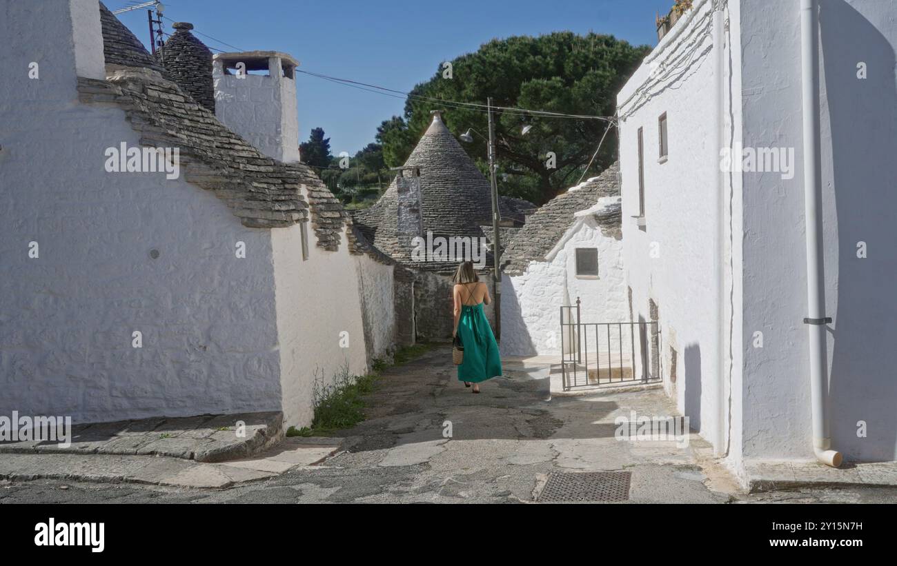 A young hispanic woman in a green dress walks down a charming street in ...
