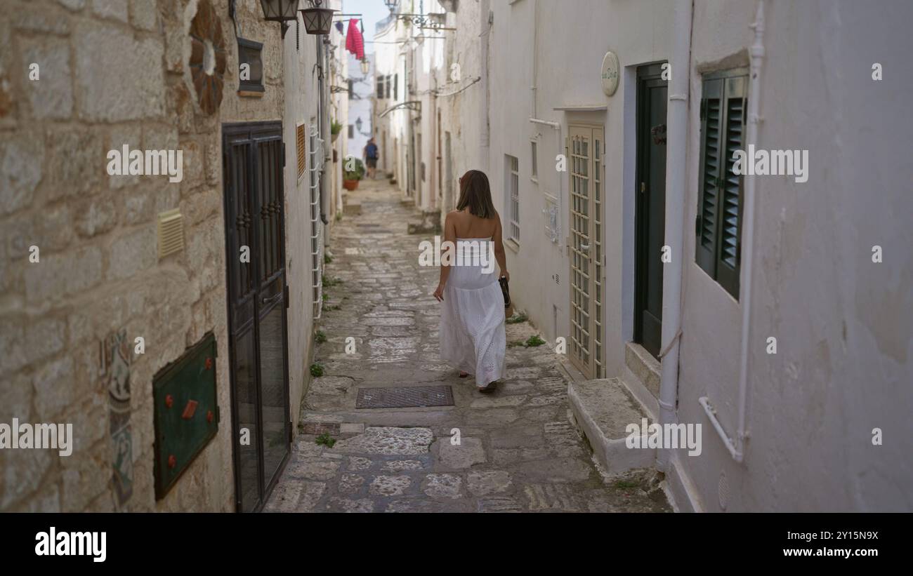A young beautiful hispanic woman in a white dress strolls through the ...