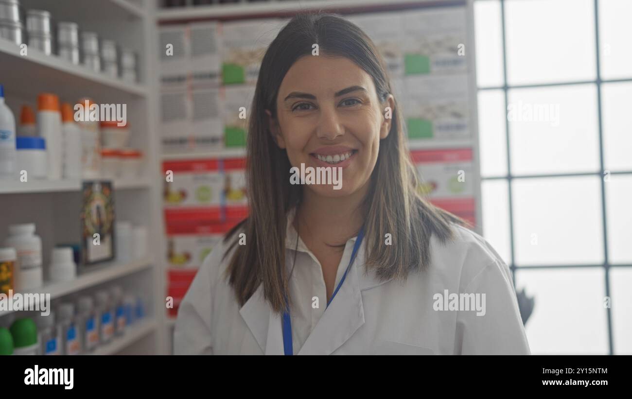 Smiling woman pharmacist standing inside a drugstore with shelves of ...