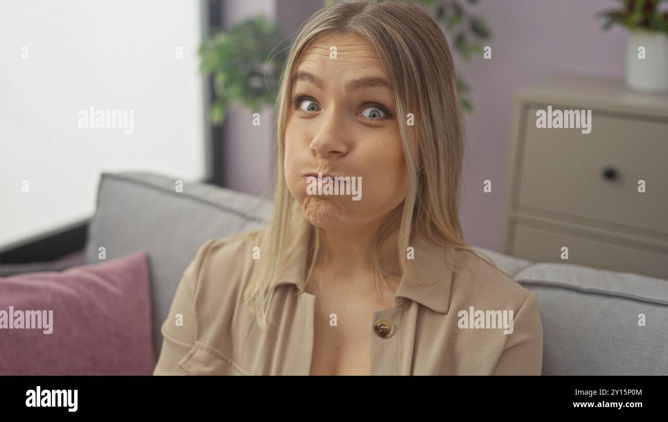 A young attractive blonde woman making a funny face while sitting in a ...