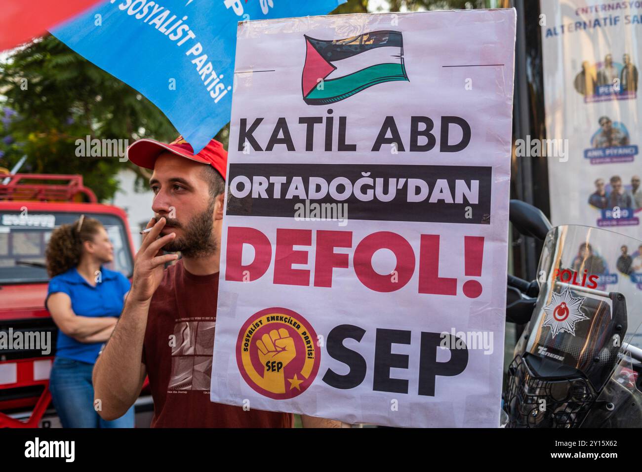 A protester smokes a cigarette while holding a placard saying ...