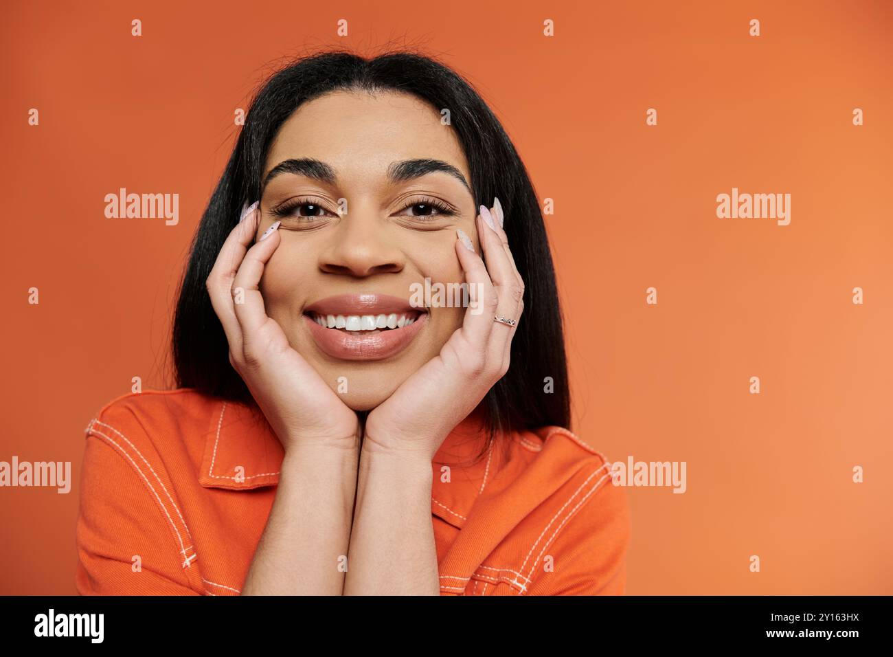 A smiling woman embraces happiness with her hands on her cheeks Stock ...