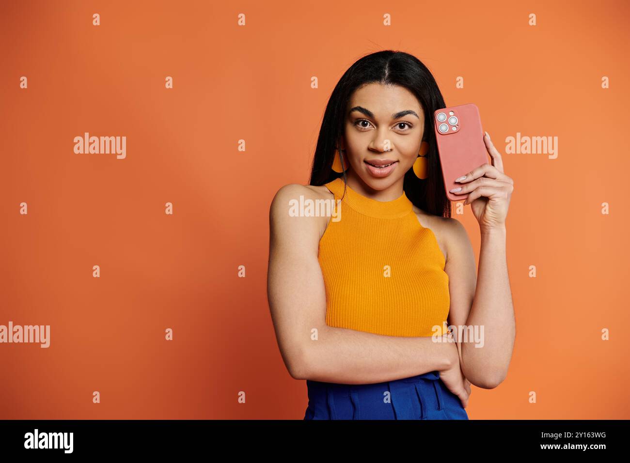 Confident woman showcases smartphone while striking a playful pose ...