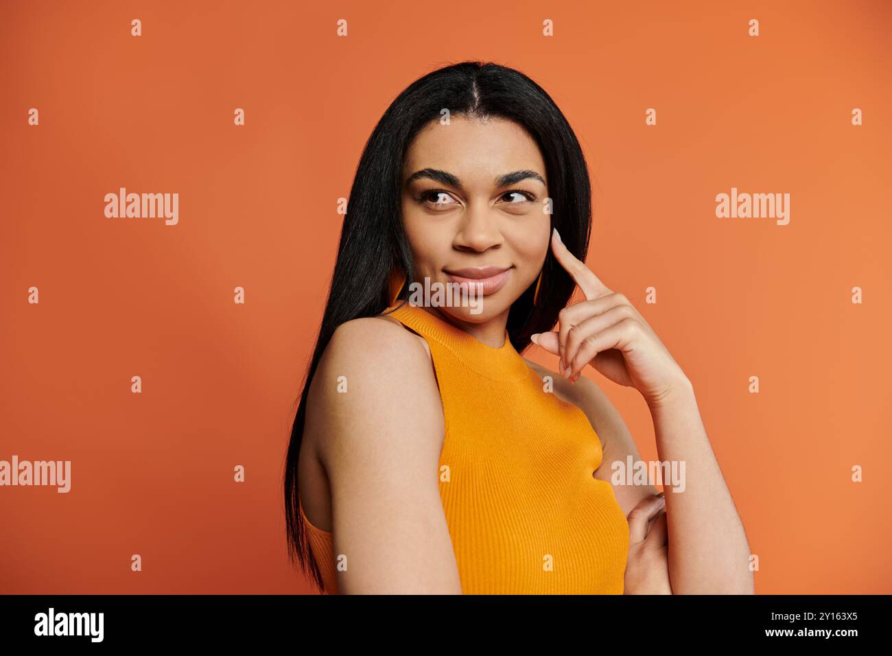 A woman exudes confidence and grace while showing a playful expression ...