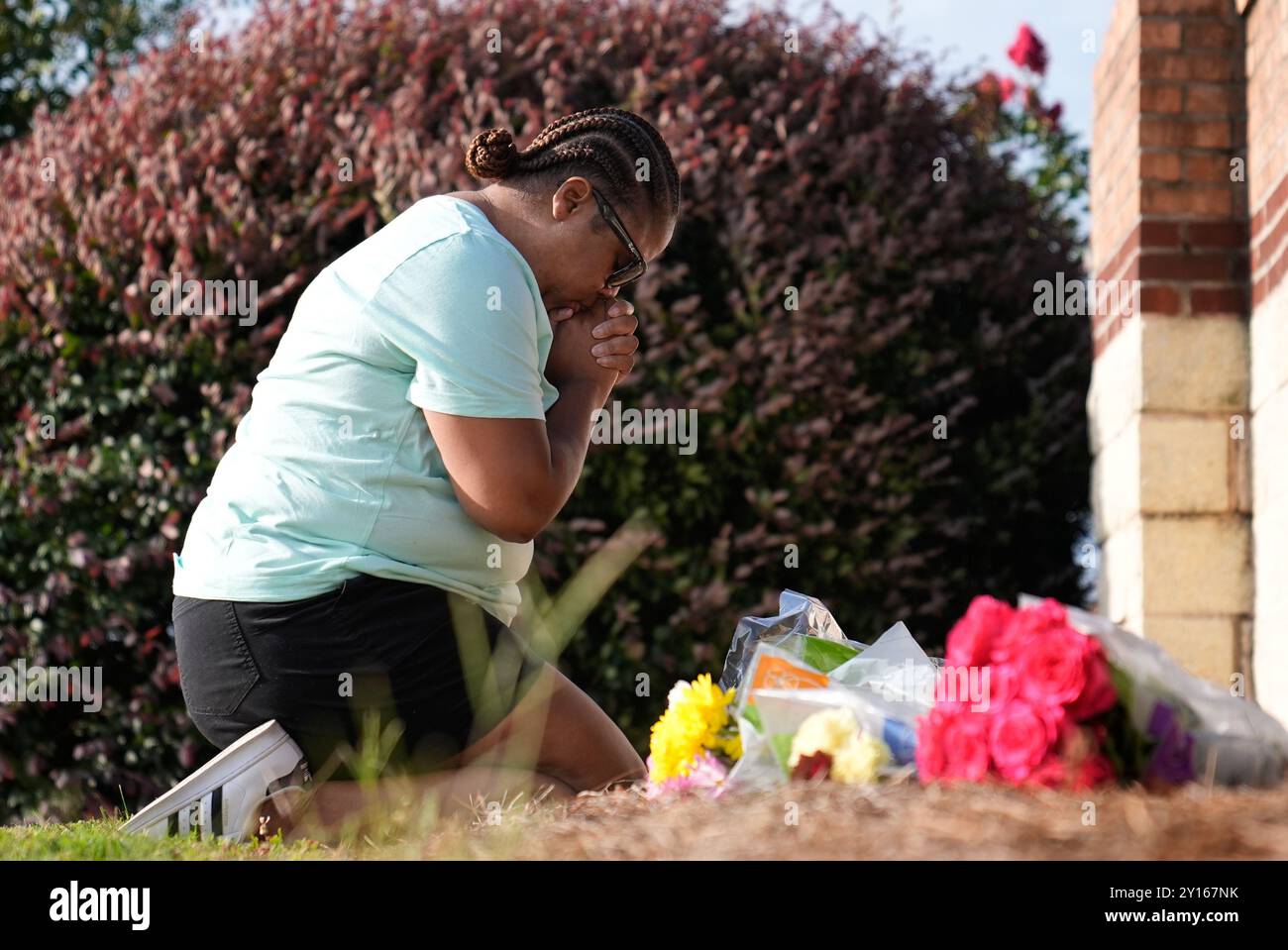 Linda Carter, of Grayson, Ga., kneels near Apalachee High School to ...