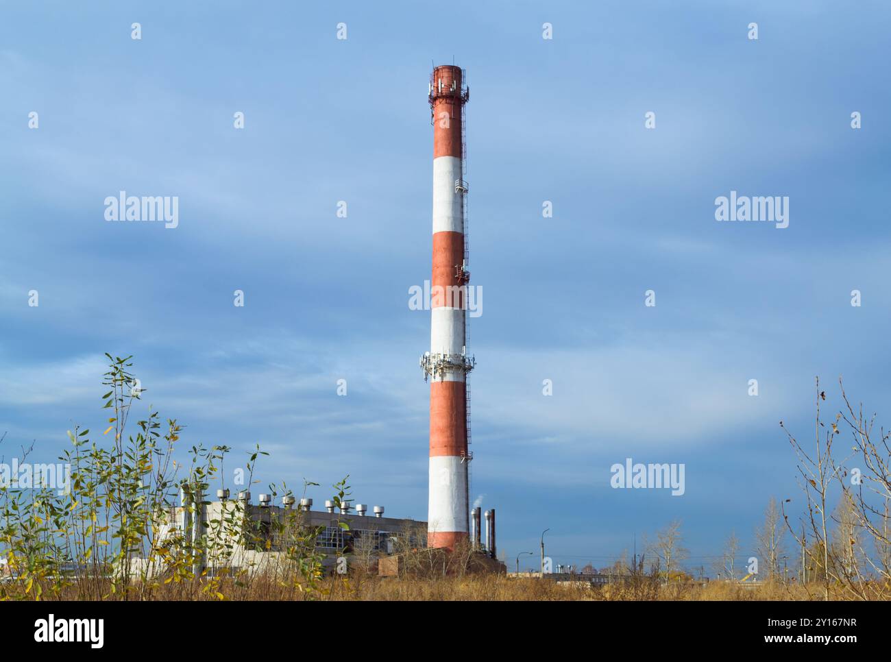 A boiler room building with a high chimney in an autumn field under an ...