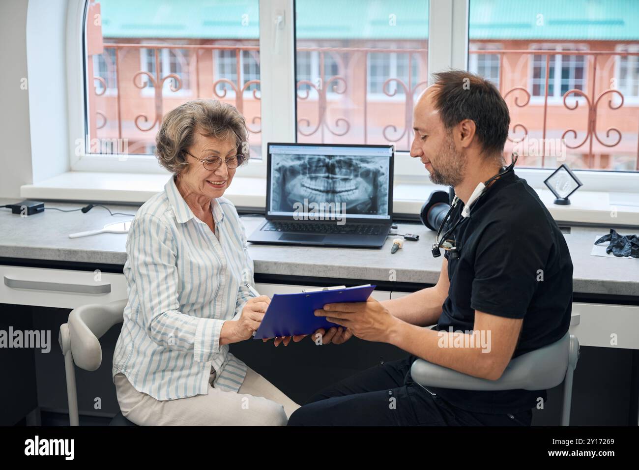 Elderly woman signing contract in dental clinic office Stock Photo - Alamy