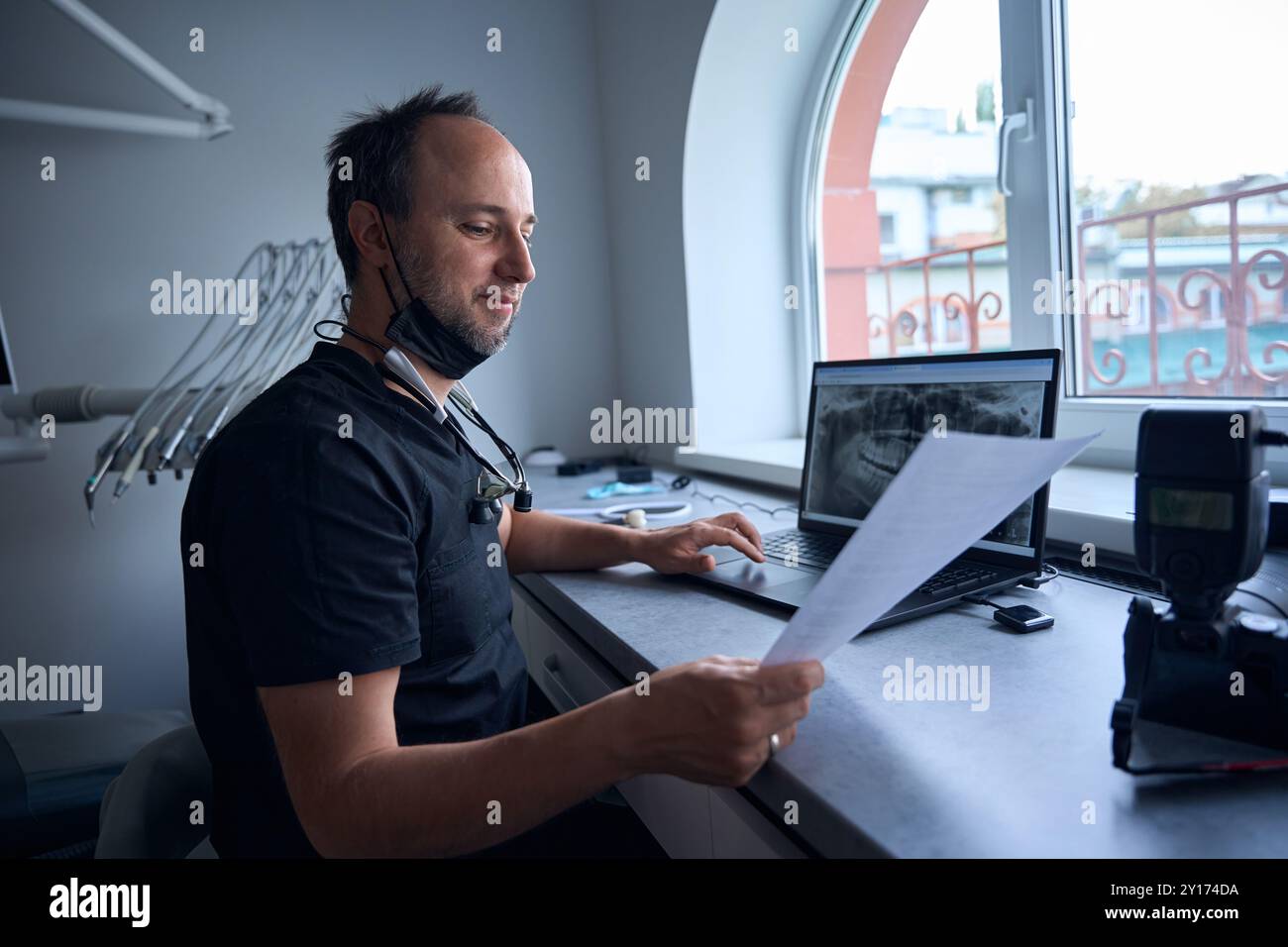 Doctor studies X-ray of row of teeth and working documents Stock Photo ...
