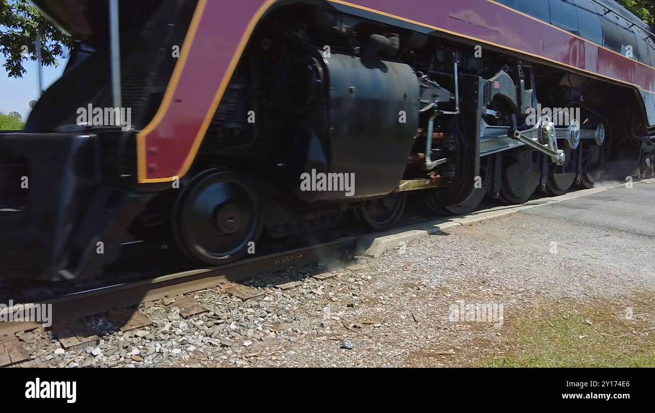 A vintage steam locomotive rolls by on the tracks, with heavy wheels ...