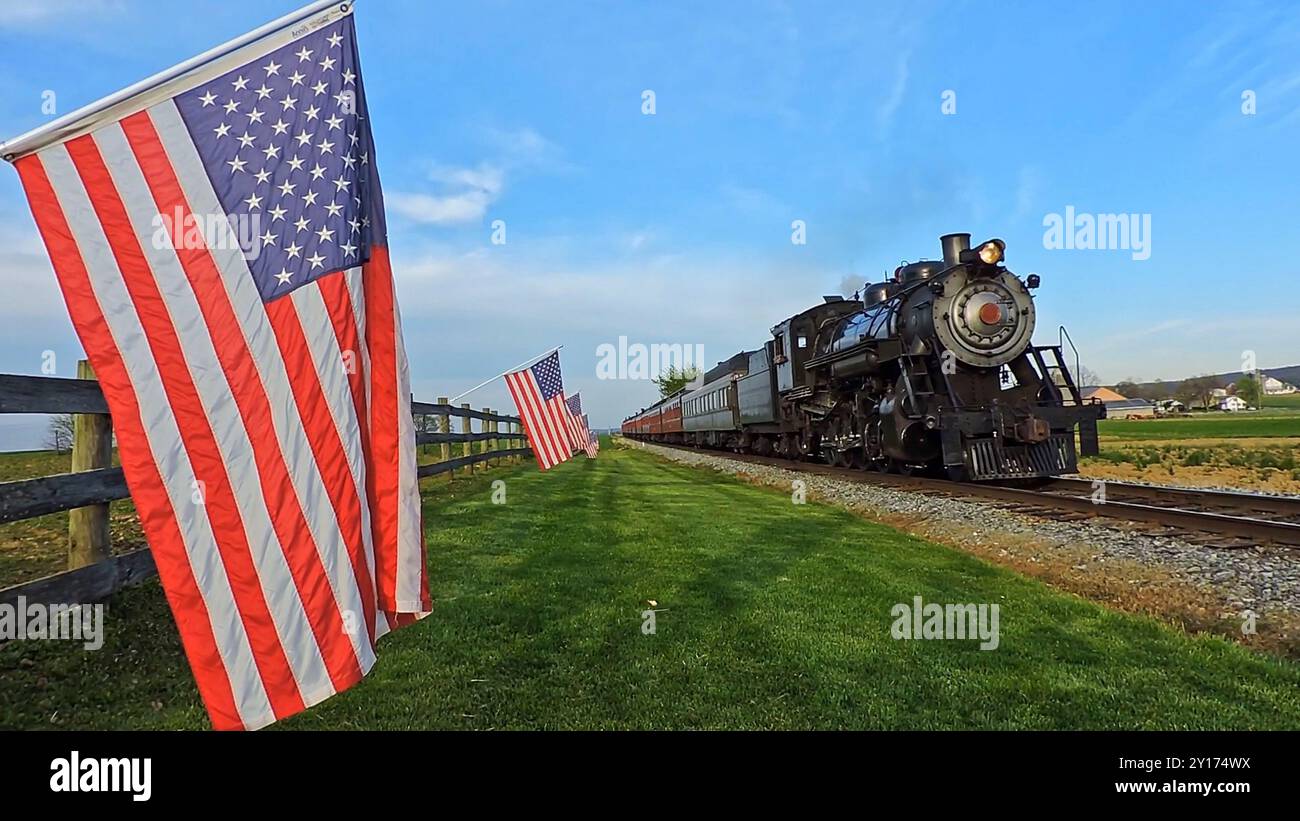 A vintage steam train moves through a scenic landscape, flanked by ...