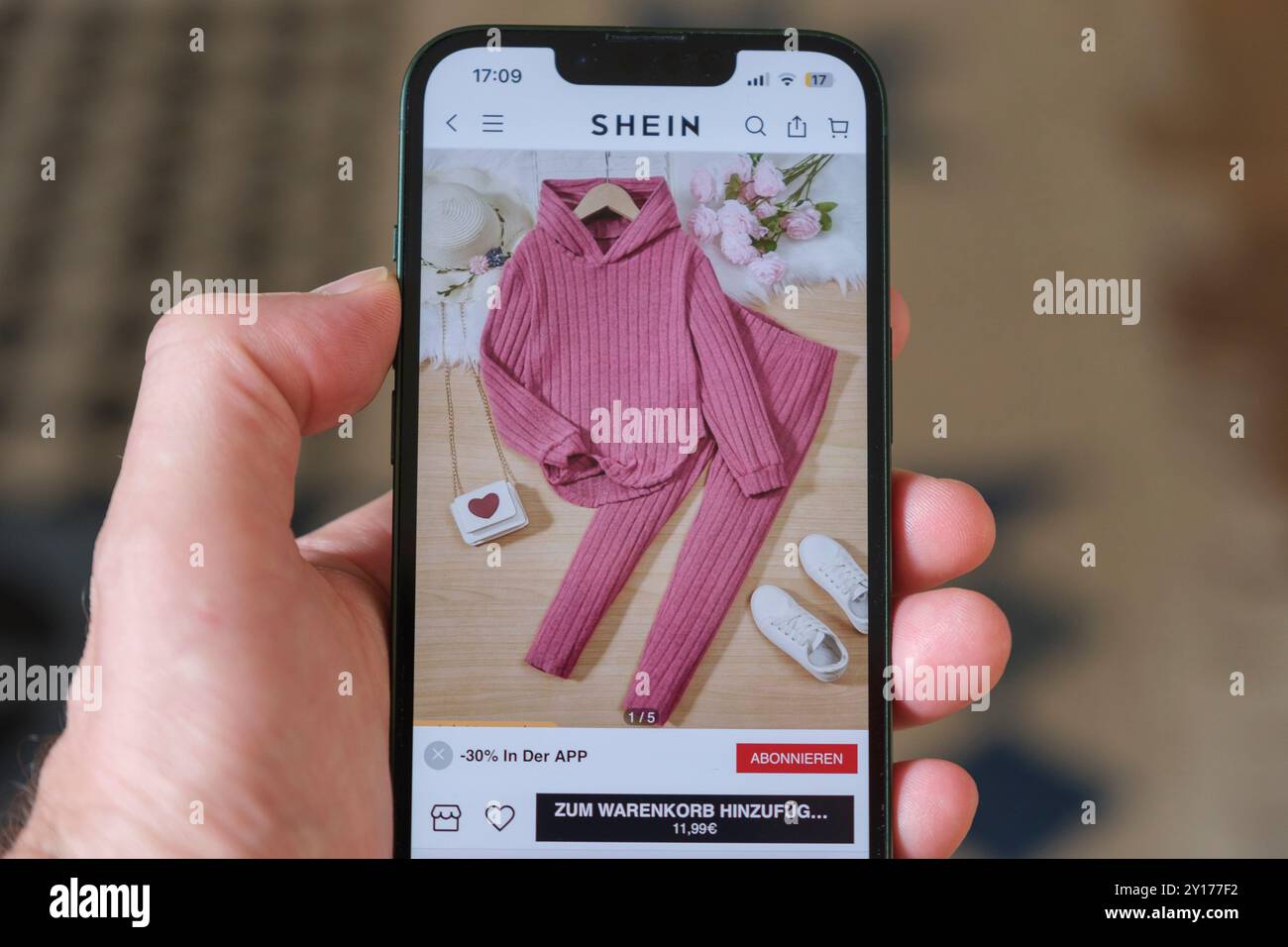 Hand holding a mobile phone showing the website of the Chinese company ...