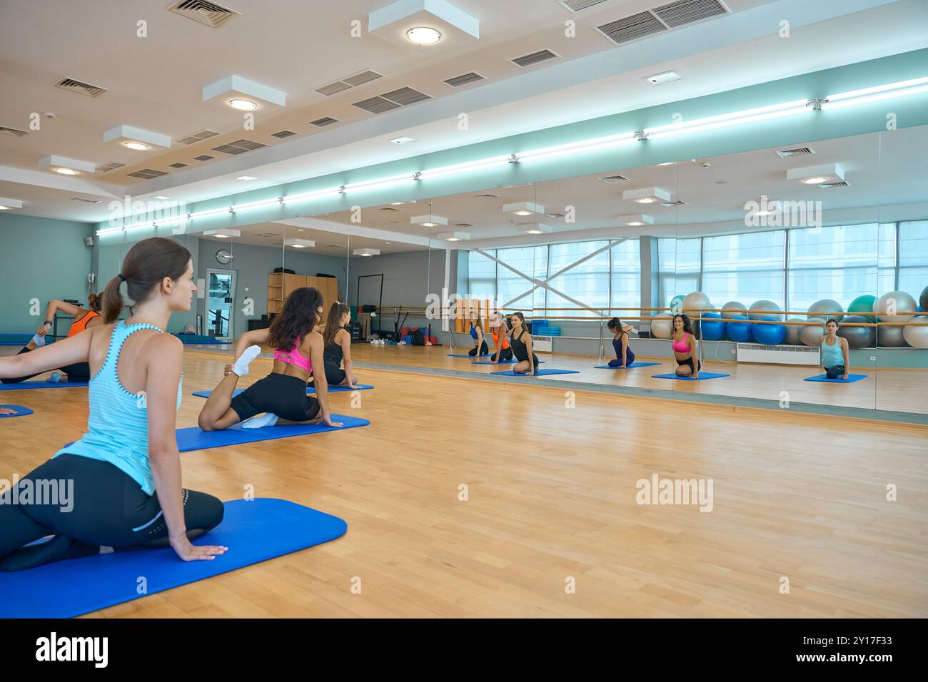 Group of women perform stretching exercises in training room on floor ...