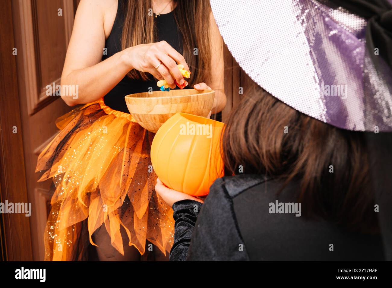 On Halloween hand of a girl giving candy to children from the threshold ...
