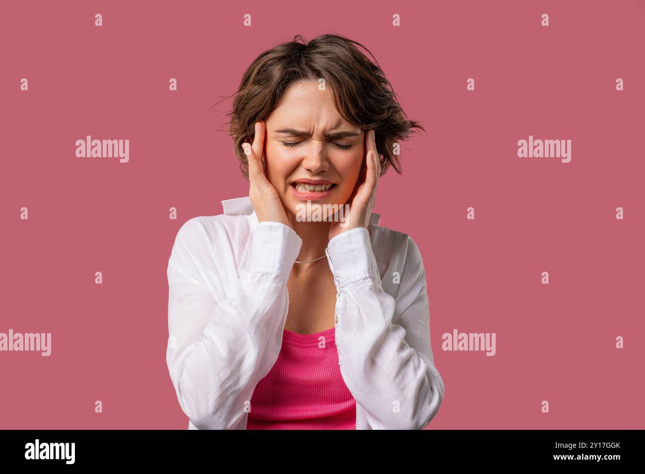 Mature woman having hypertension headache, pink studio. Putting hands ...