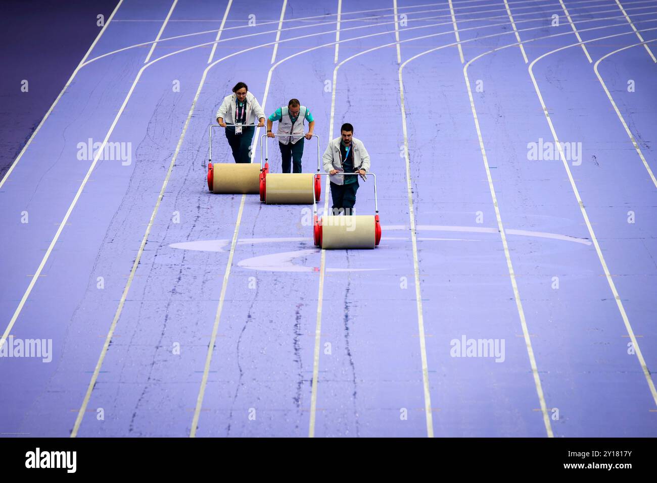Volunteers clean the track during the athletics competitions at the ...