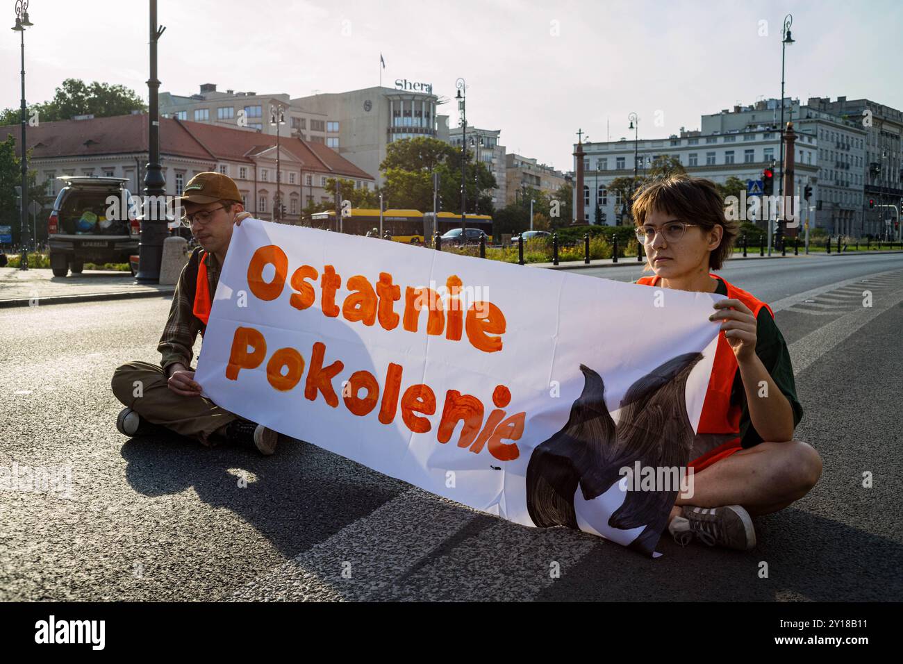 Climate activists block the road and hold a banner bearing the name of ...