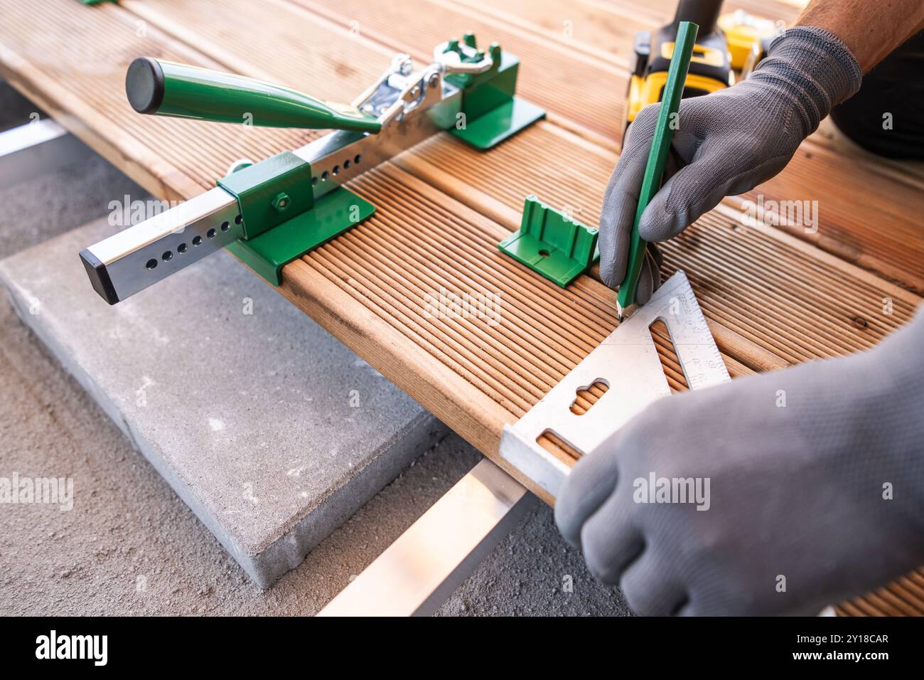 A person measures and marks wood for deck construction, utilizing a ...