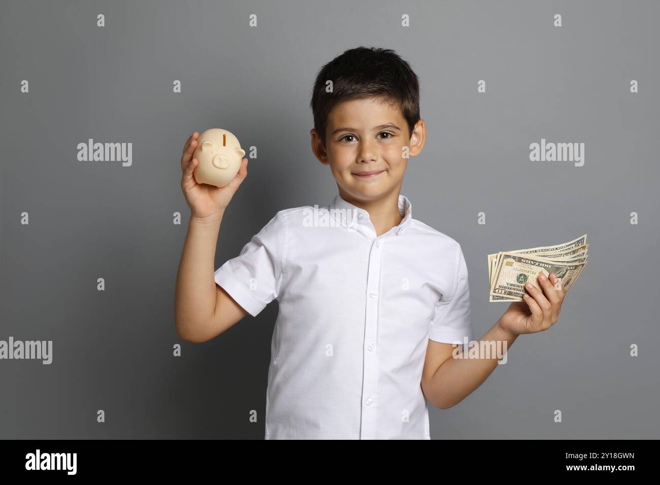 Cute boy with piggy bank and pocket money on grey background Stock ...