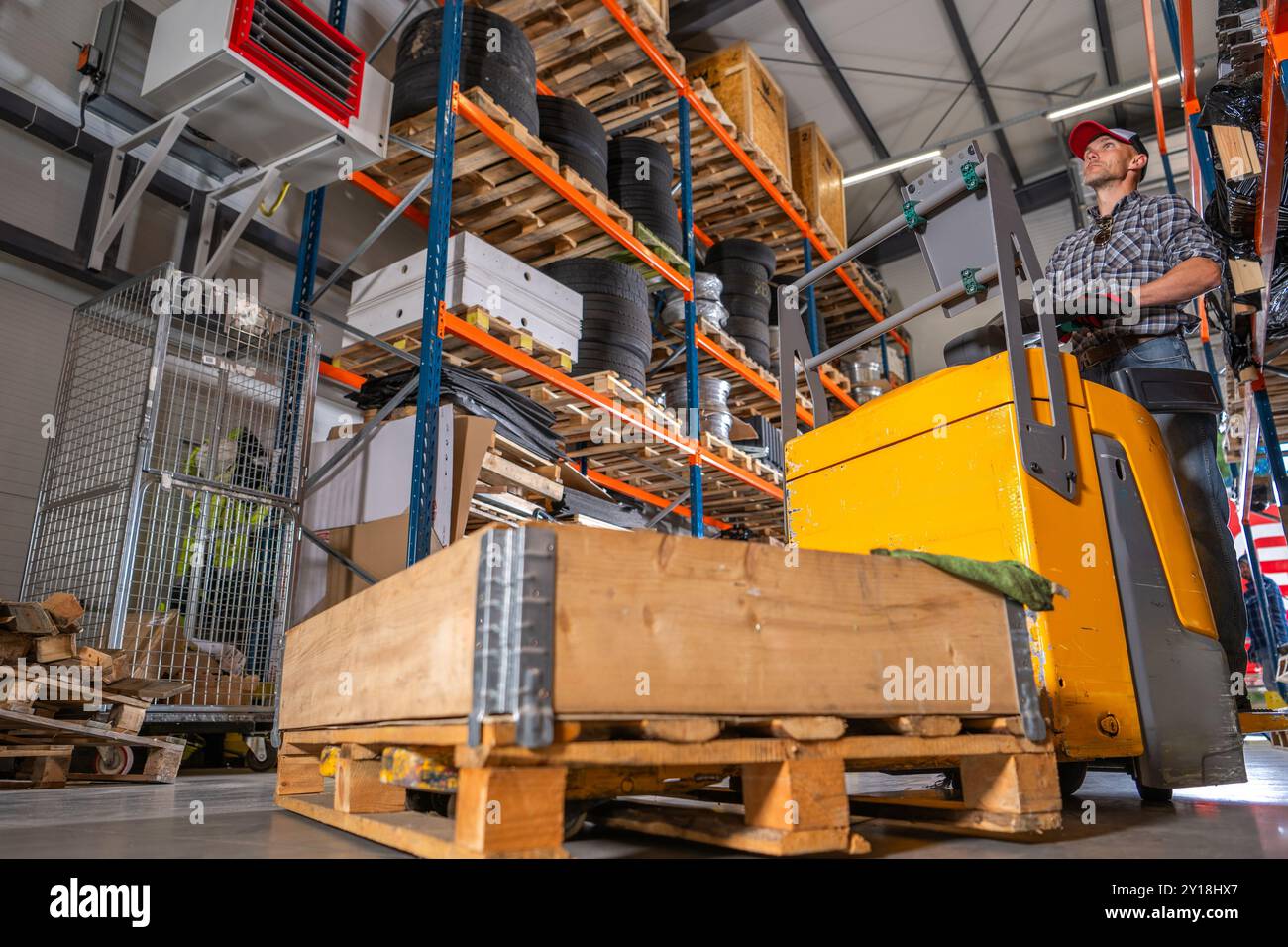 A worker uses a pallet truck to move wooden crates in a well-organized ...