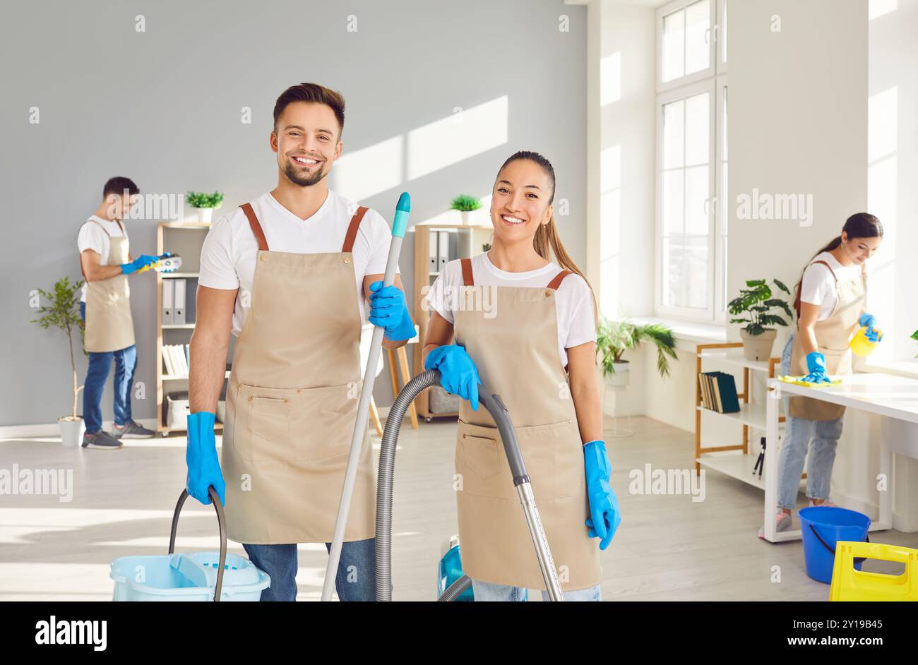 Young janitors looking at camera with a team of cleaning service ...