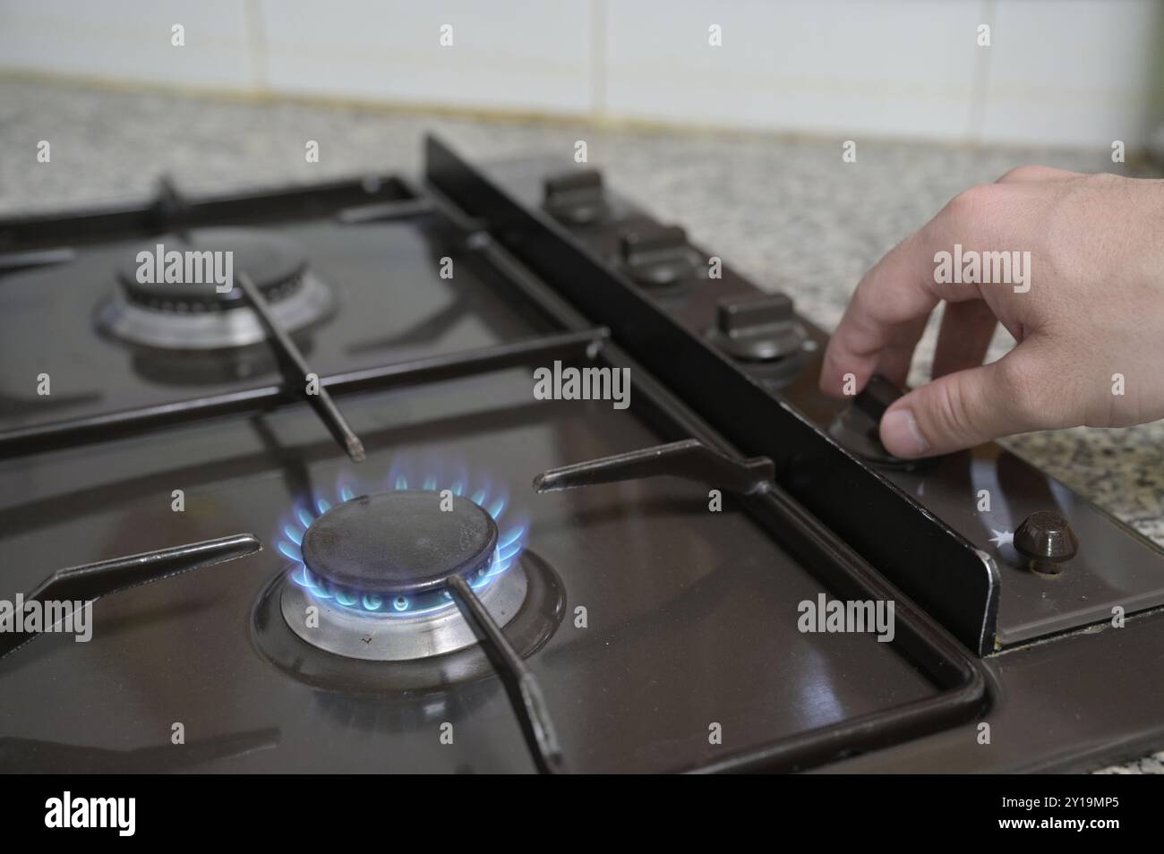 The close up of the kitchen gas is on and a hand is trying to turn it ...
