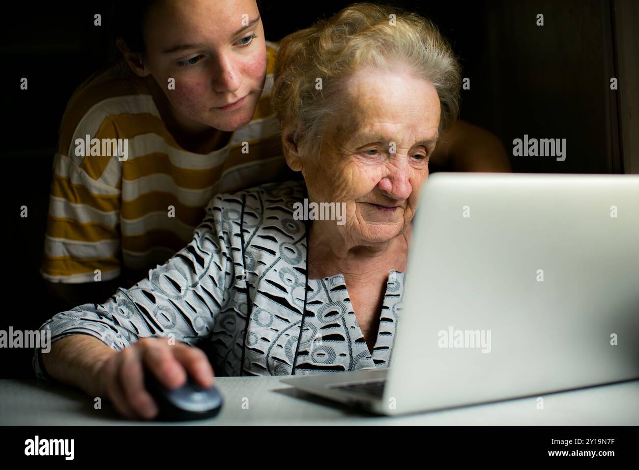 An elderly woman learns to use a computer with the guidance of her ...