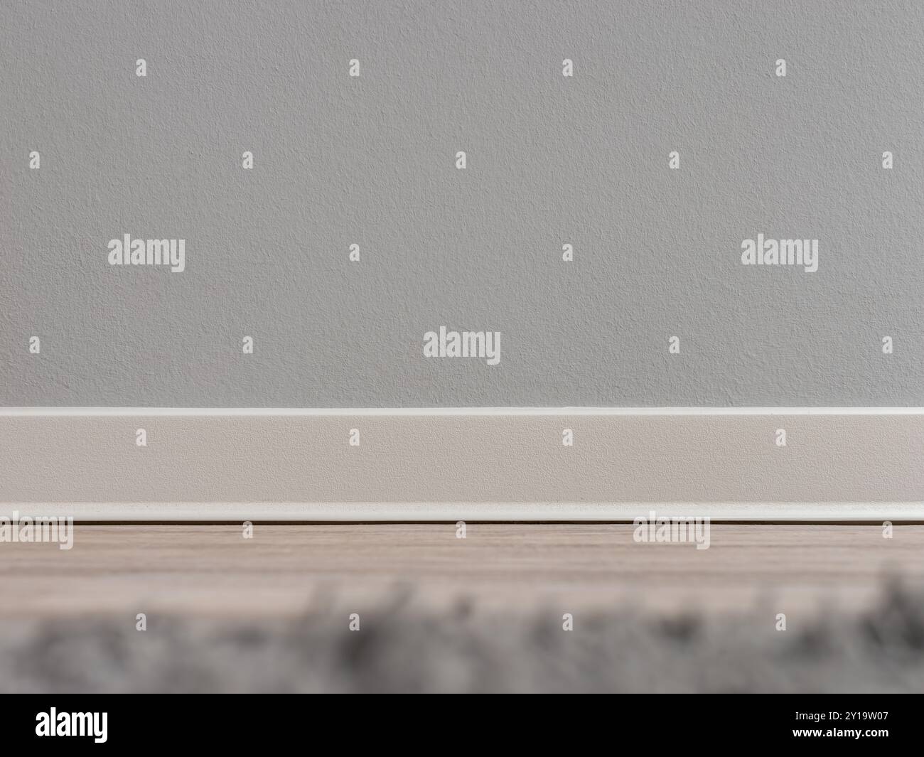 Empty wall with a baseboard. Grey background and a bright wooden floor ...