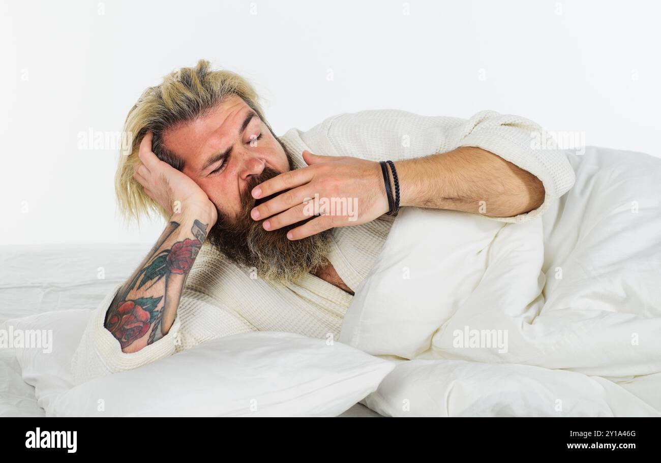 Good morning. Bearded man yawning in bed after sleeping. Handsome man ...
