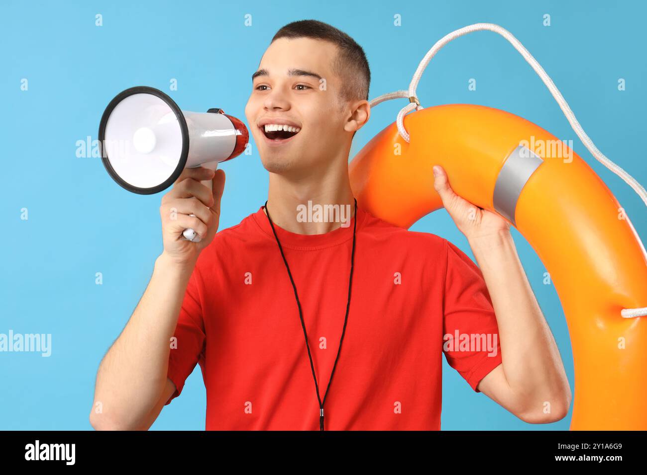 Male lifeguard with ring buoy shouting into megaphone on blue ...