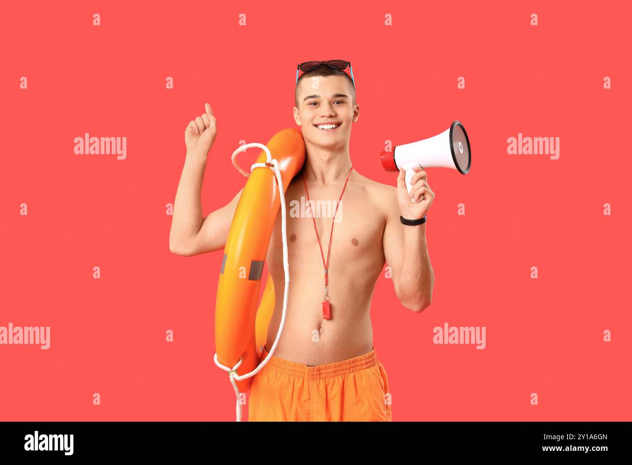 Male lifeguard with ring buoy and megaphone pointing at something on ...
