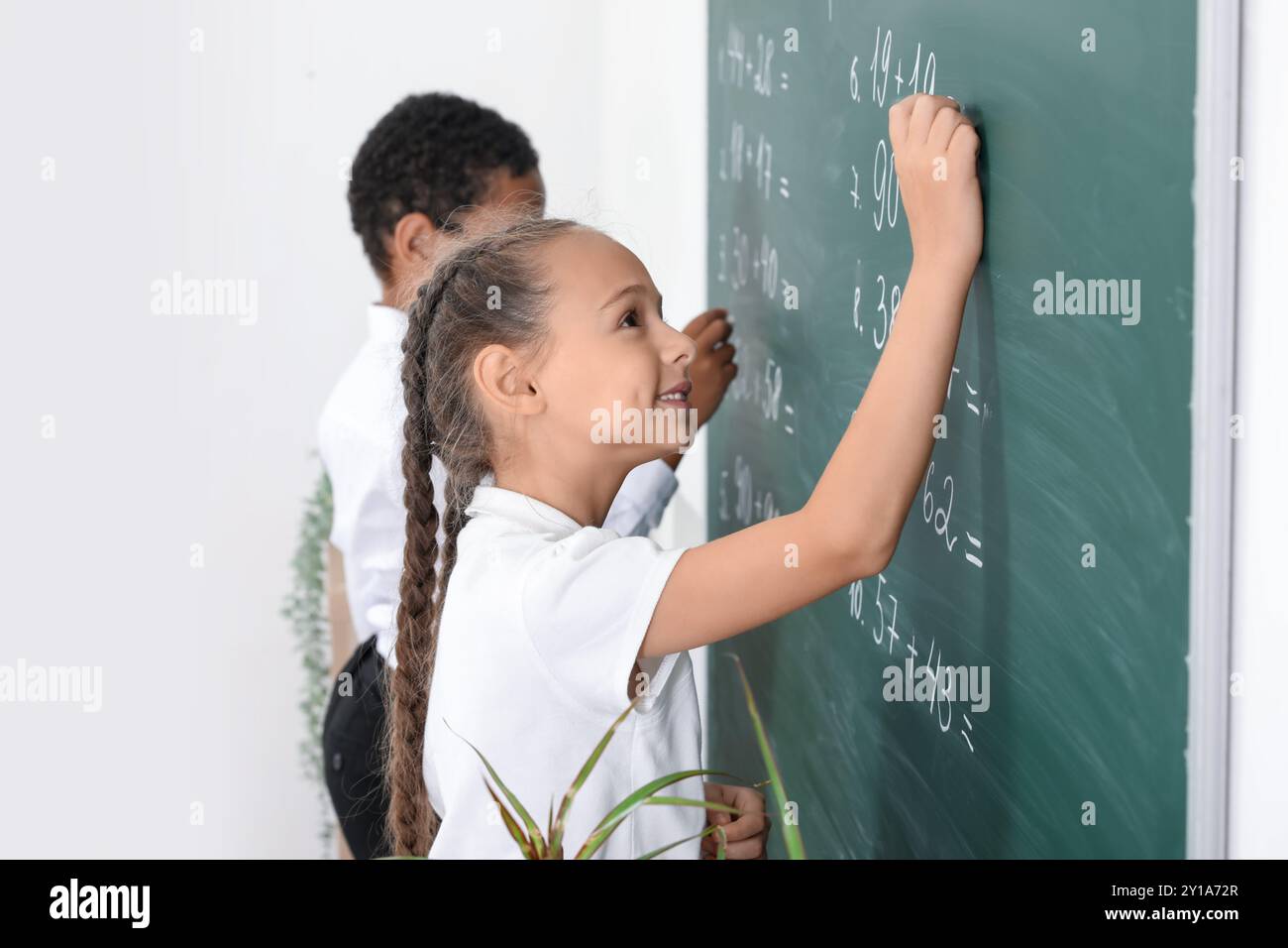 Little classmates writing on chalkboard in classroom Stock Photo - Alamy