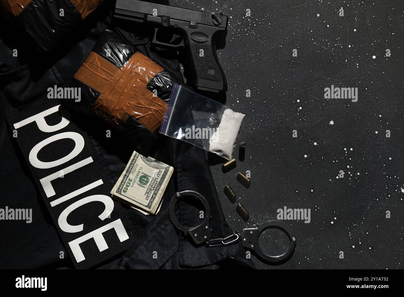 Drug packages with gun, handcuffs and police uniform on dark background ...