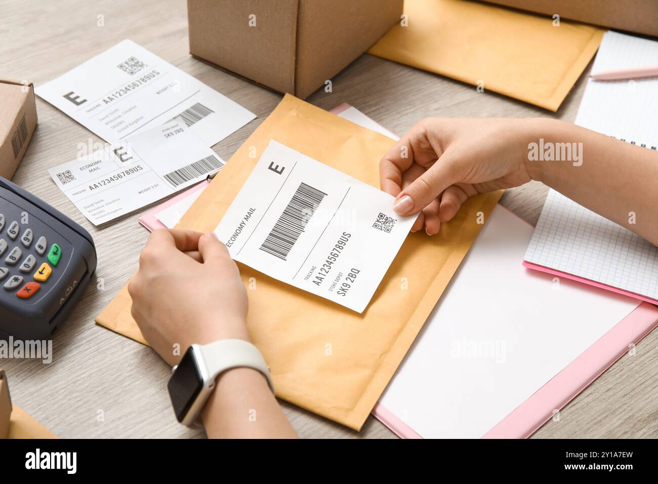 Female postal worker sticking label to package on table, closeup Stock ...