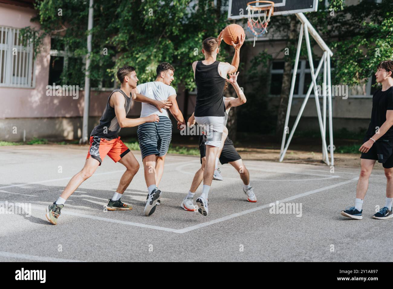 Friends enjoying a competitive game of basketball on an old ...
