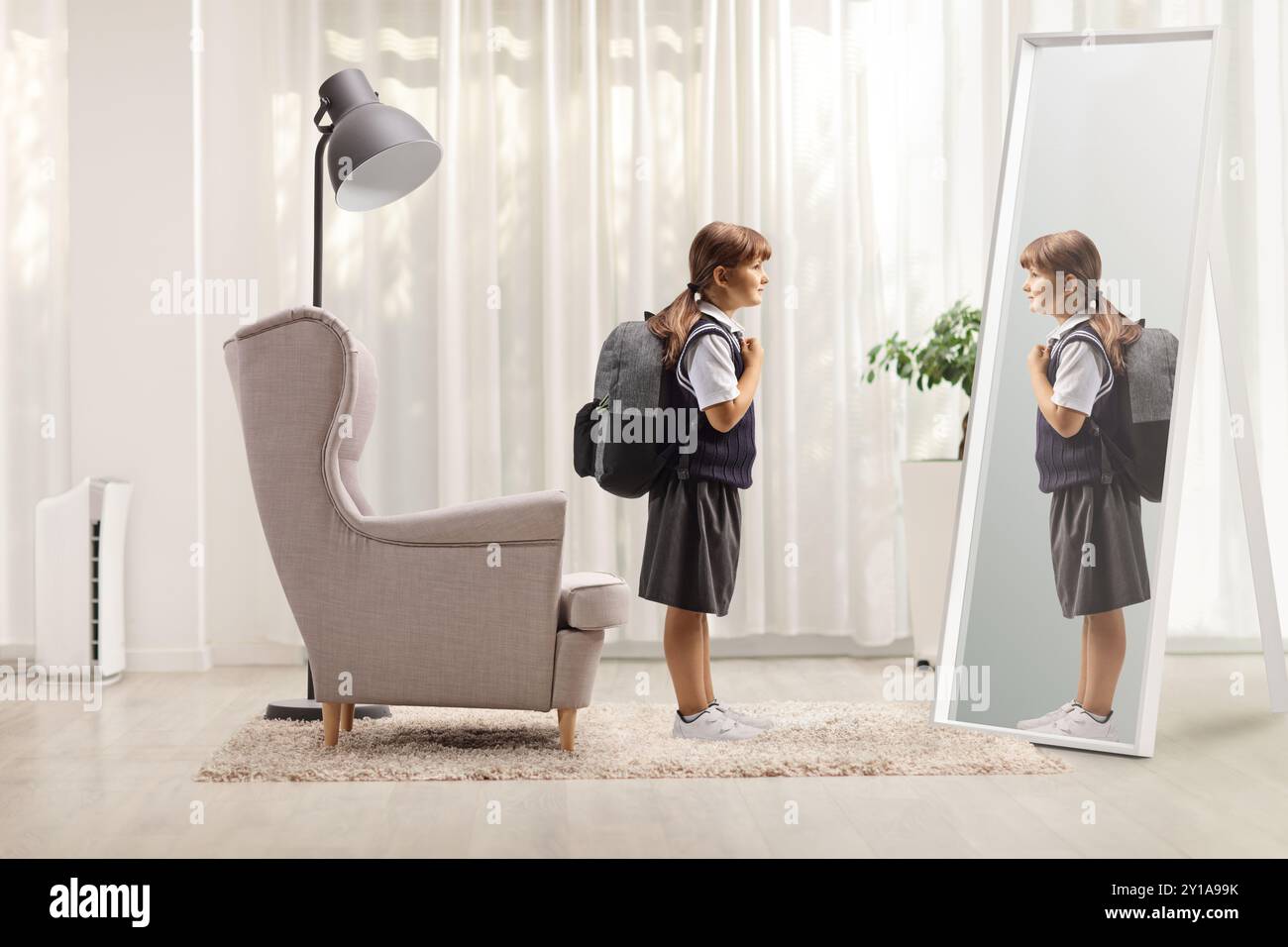 Girl in a school uniform standing in front of a mirror at home Stock ...