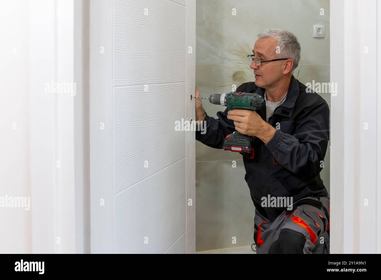Installation of a lock on the wooden door. Screwdriver is used by ...