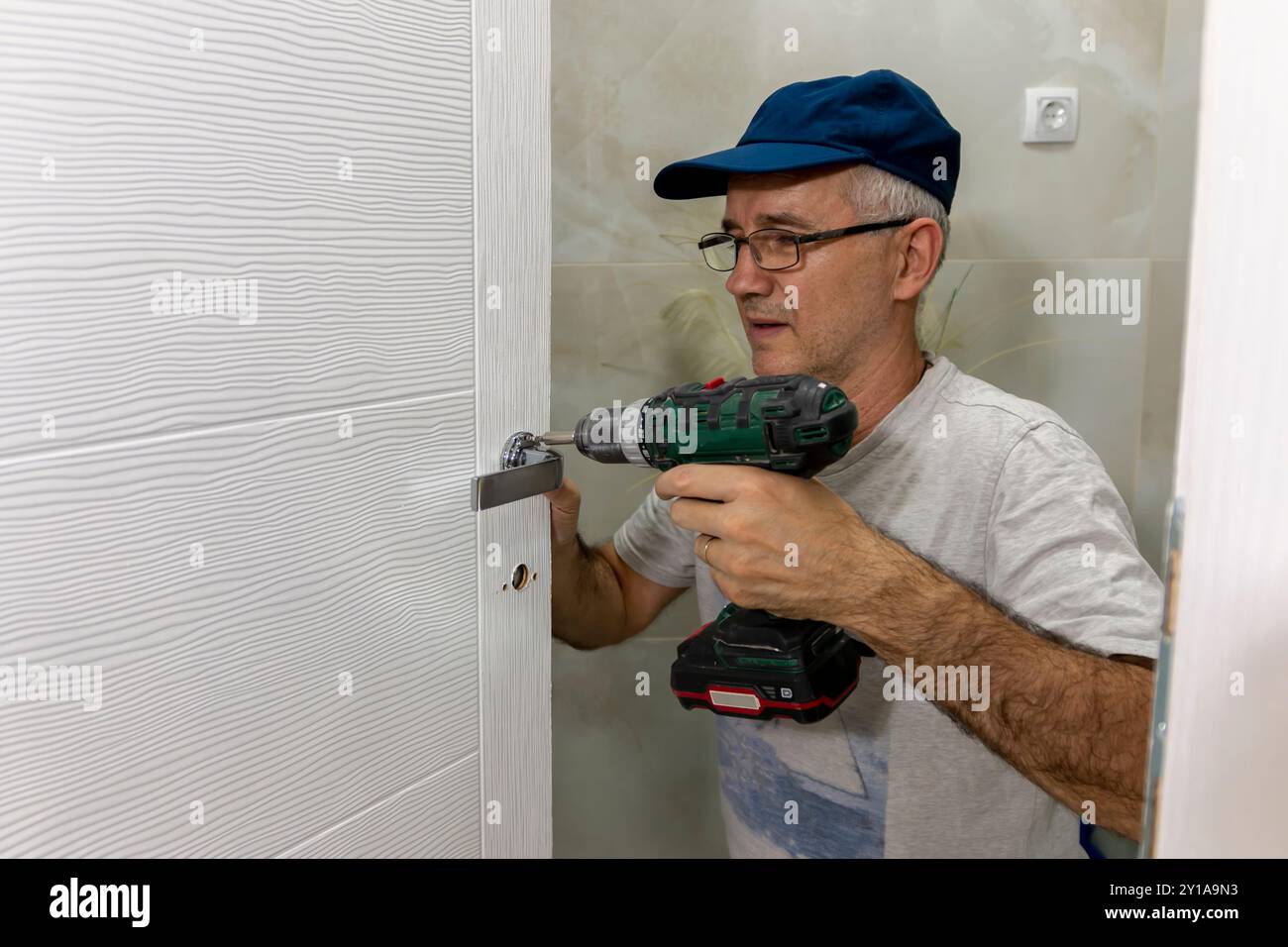 Installation of a lock on the wooden door. Screwdriver is used by ...